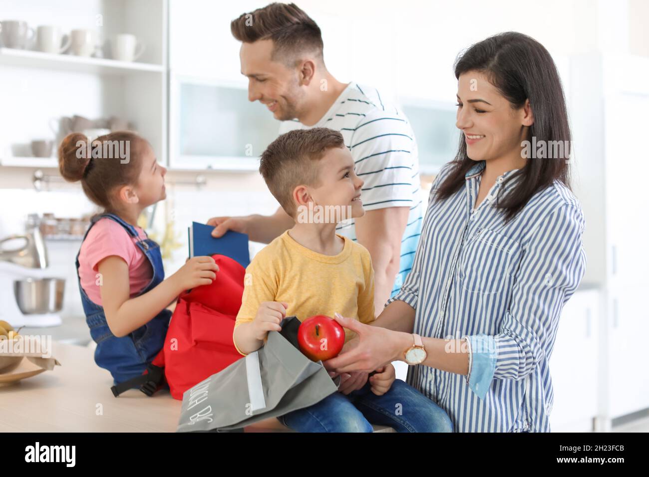 Young parents helping their little children get ready for school at ...
