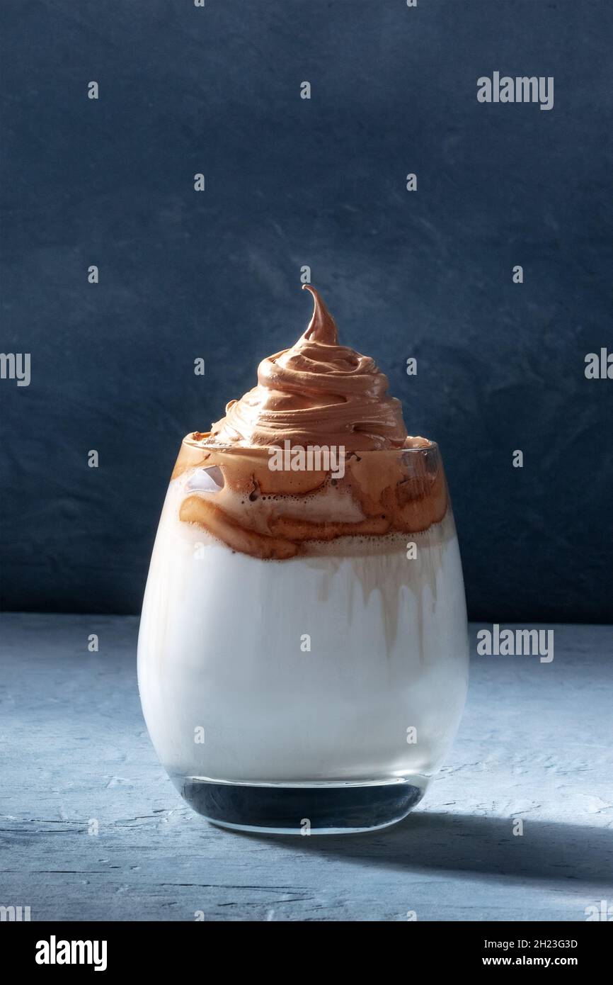 Dalgona cold coffee in a glass on a dark blue background with copy ...