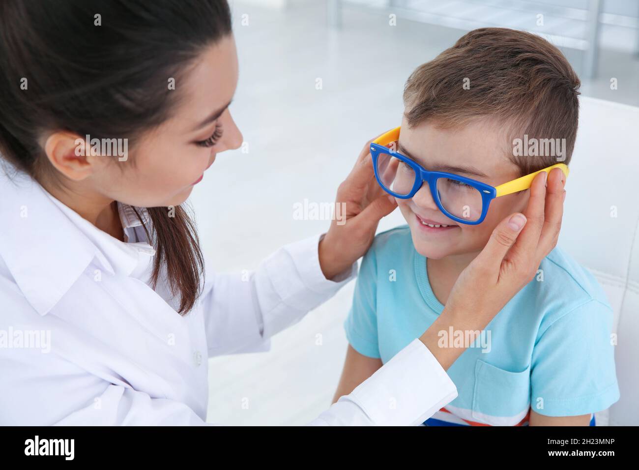 Children's doctor putting glasses on little boy in clinic Stock Photo ...