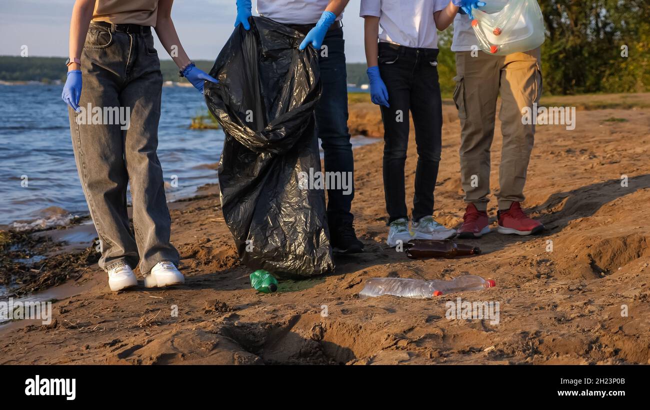 unrecognizable family collects plastic trash in bags near the coast ...