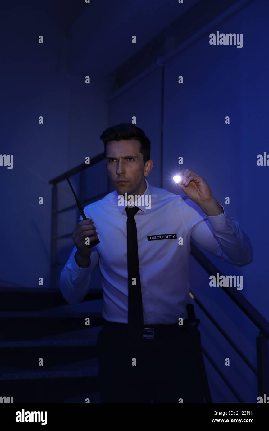 Male security guard with flashlight and portable radio transmitter in ...