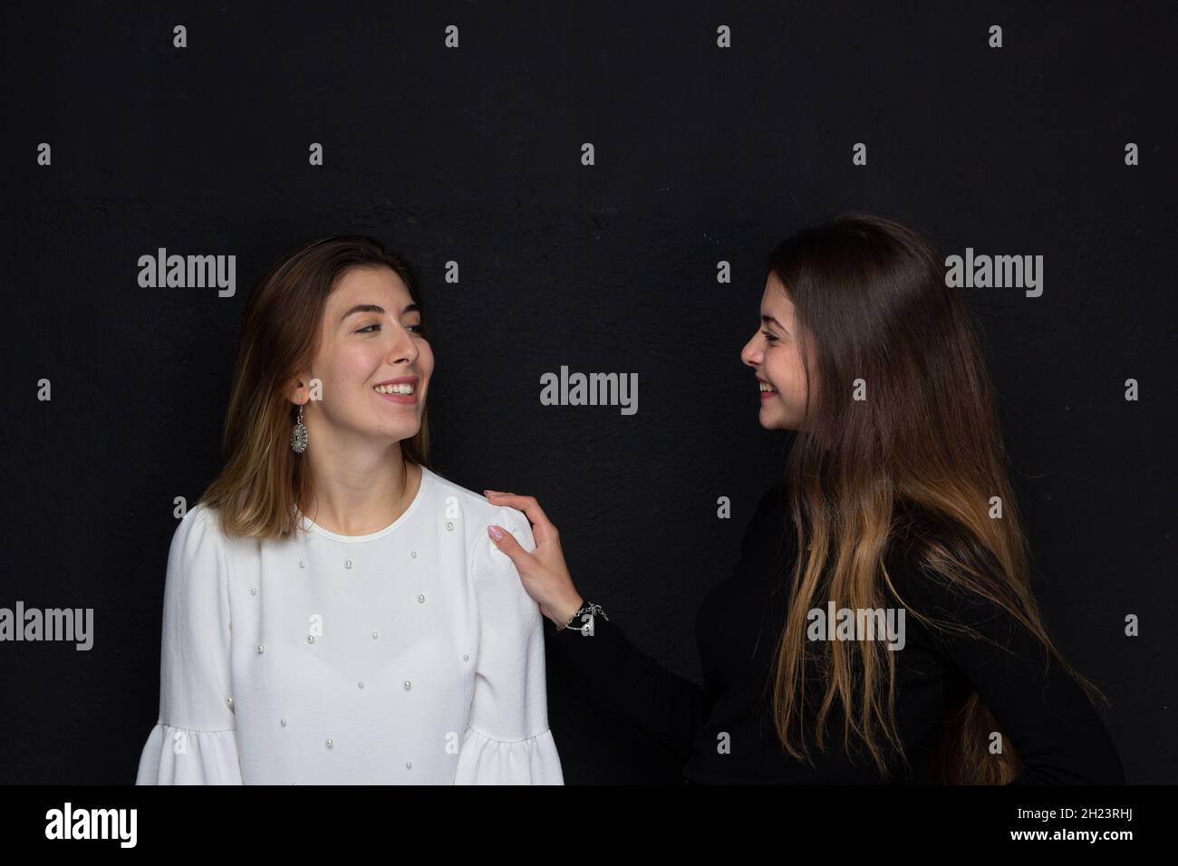 Two friends talking in a friendly way smiling on a black background ...