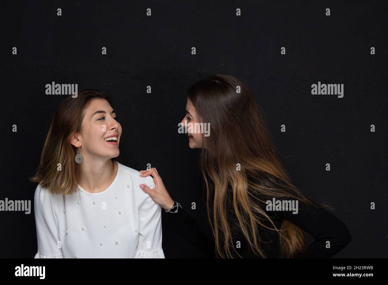 Two friends talking in a friendly way smiling on a black background ...