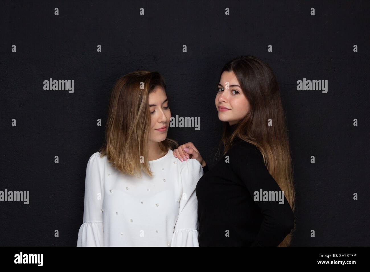 Portrait of two women friends with gestures of affection on a black ...