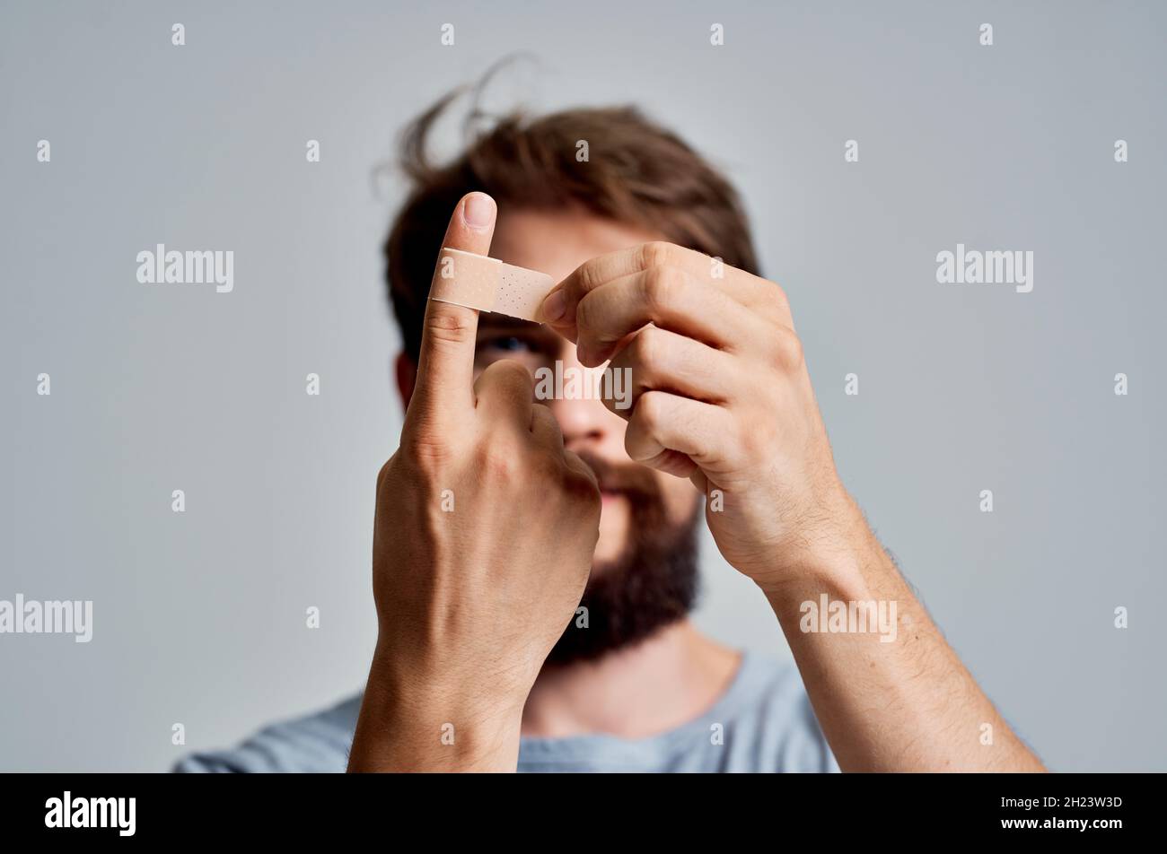 bearded man sticks his finger with a plaster treating health problems ...