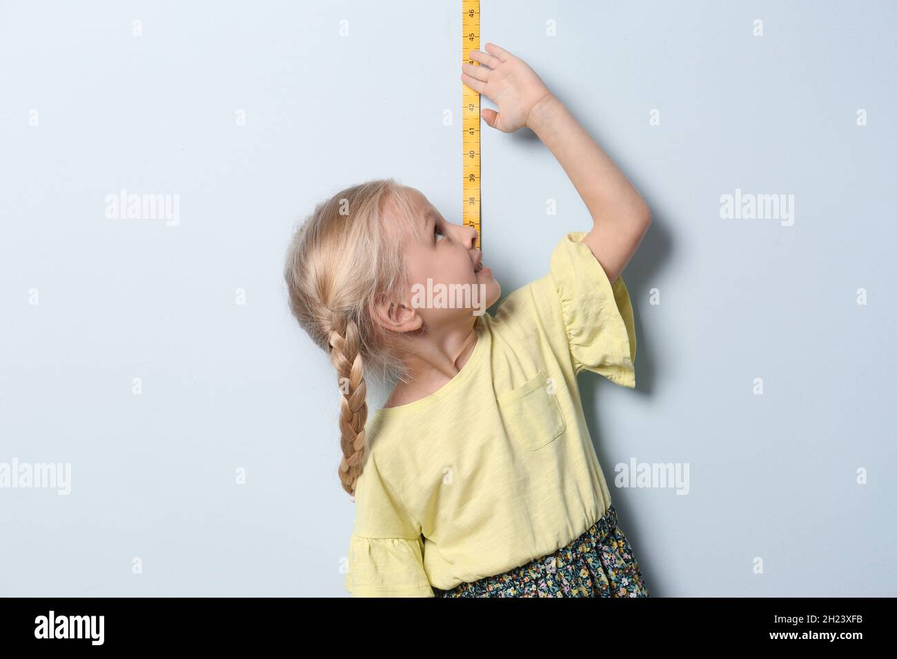 Little girl measuring her height on light background Stock Photo - Alamy