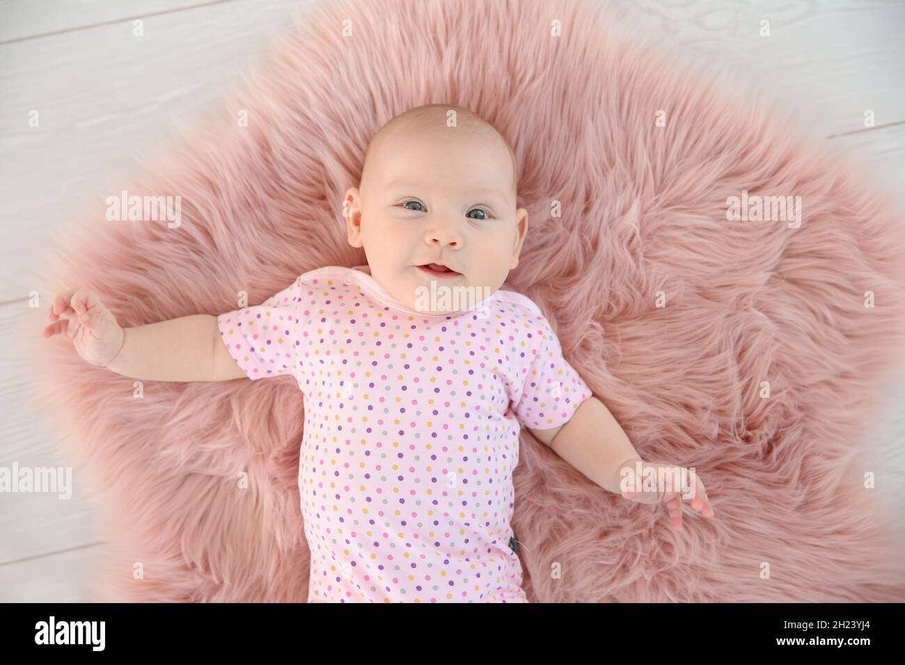 Adorable baby girl lying on fluffy rug, top view Stock Photo - Alamy
