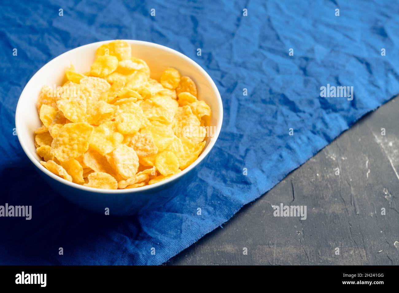 Tasty crispy corn flakes in bowl on the rustic background. Selective ...