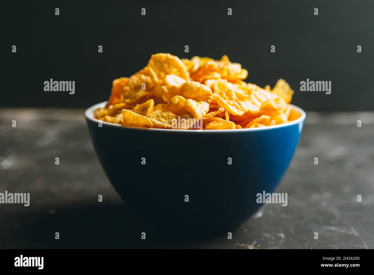Tasty crispy corn flakes in bowl on the rustic background. Selective ...