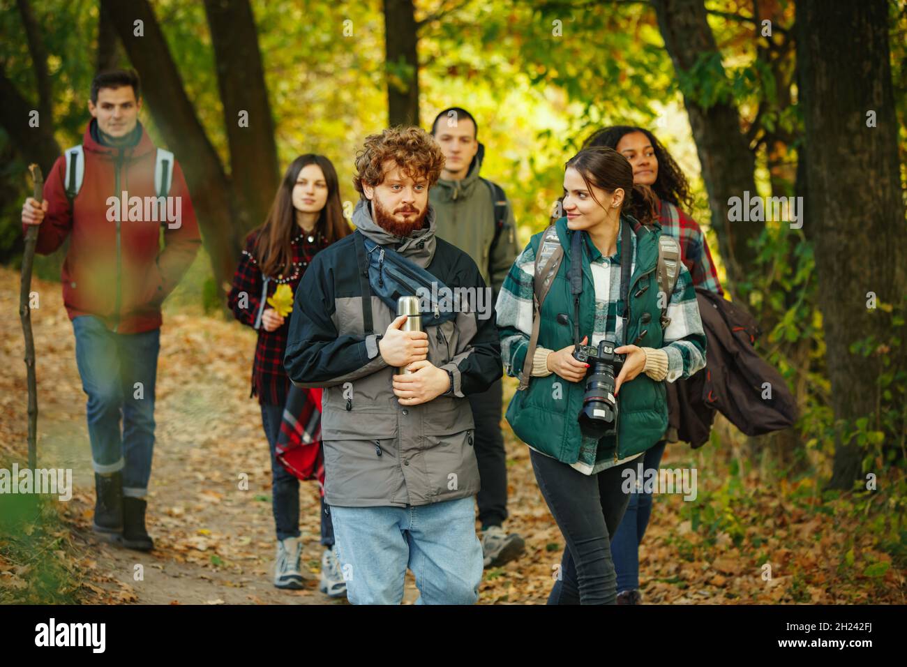 Group of joyful friends spending time together in the forest, doing ...