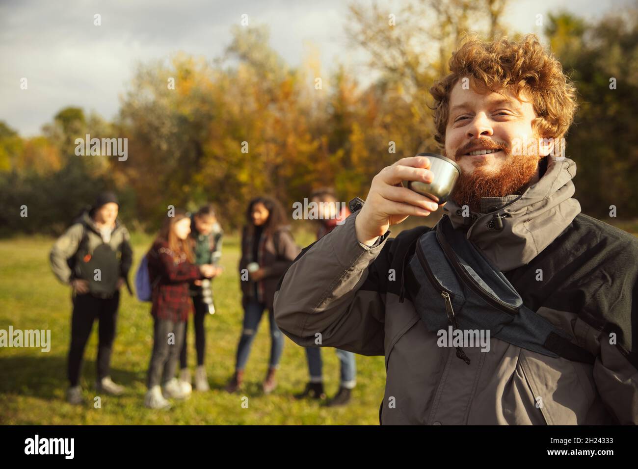 Cropped portrait of young delightful man drinking tea from thermos on ...