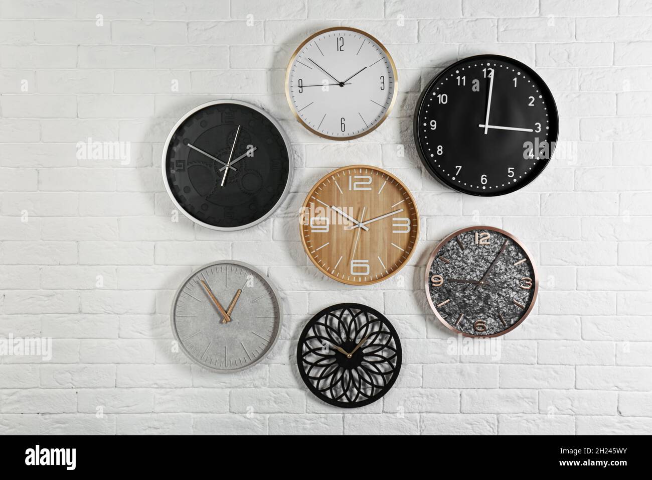 Different analog clocks hanging on white wall. Time of day Stock Photo ...