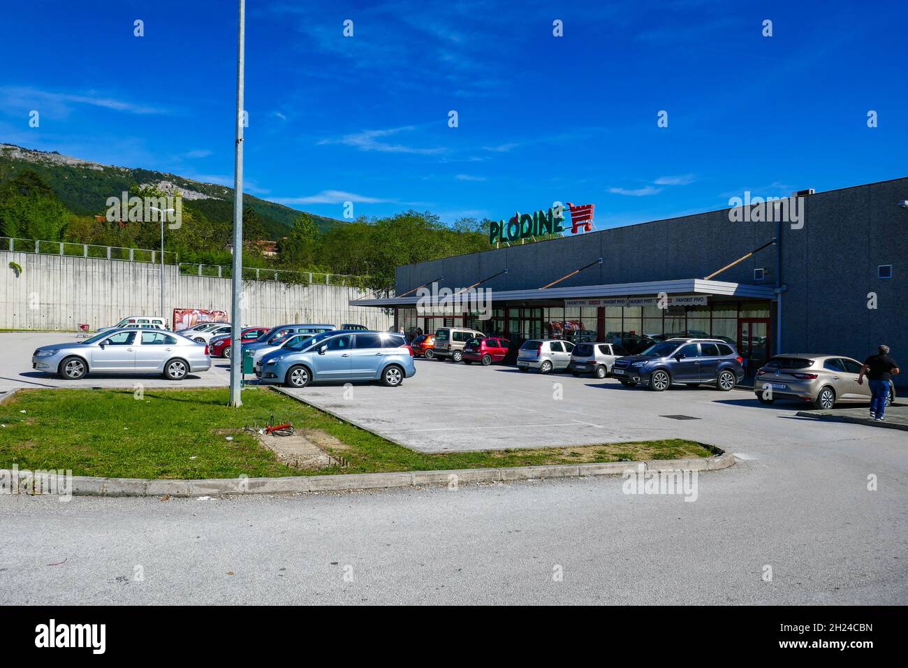 Cars parked outside Plodine, Croatian supermarket near the ancient hill ...