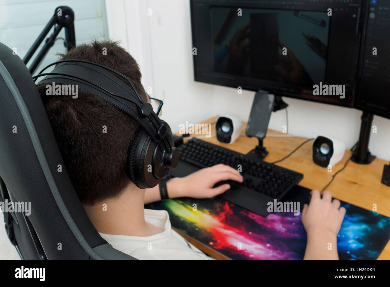 A young gamer with headphones boy playing a computer game on a powerful ...