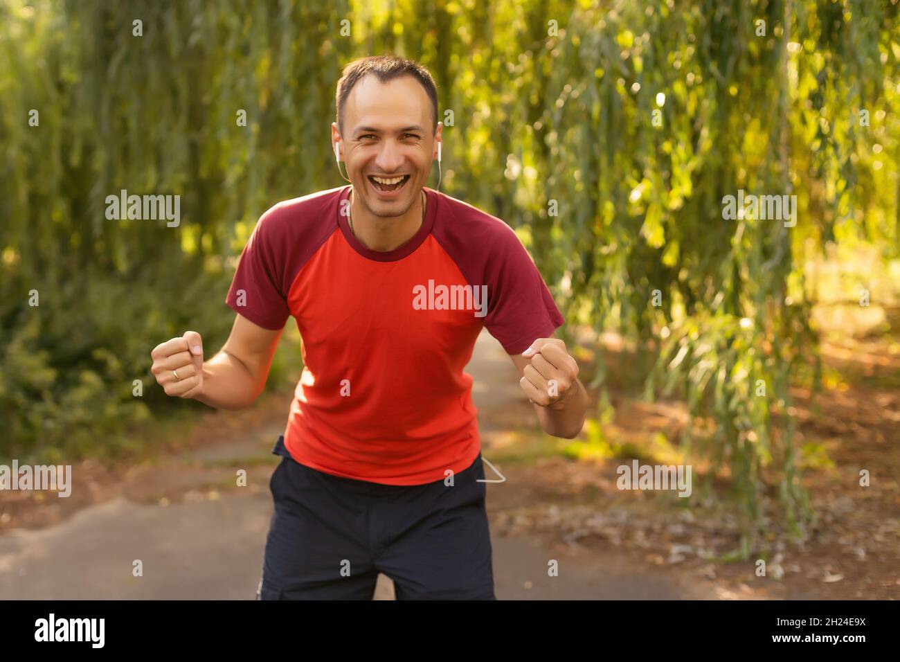 Successful man raising arms after cross track running on summer Stock ...