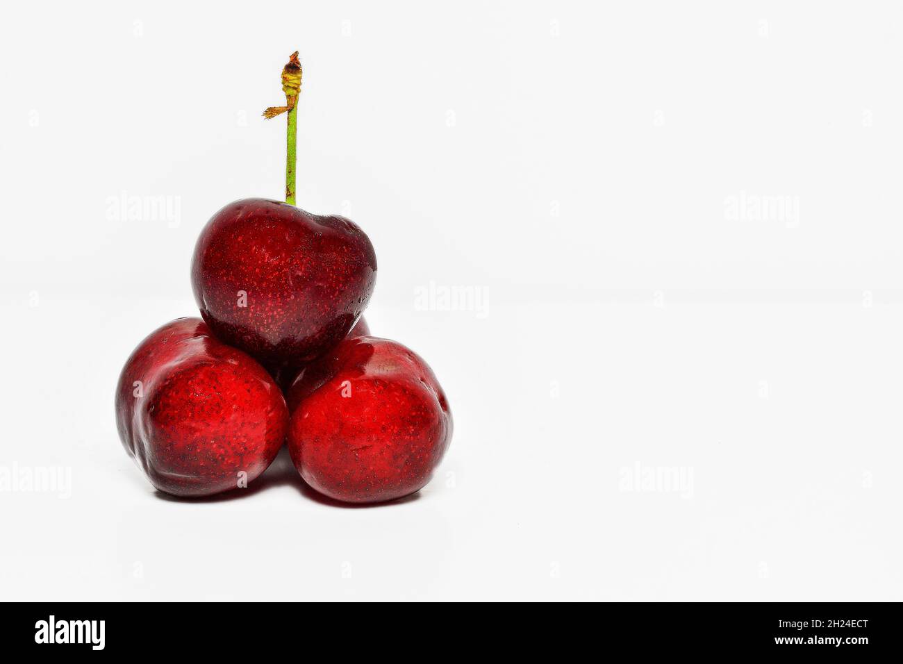 Group of three cherries on white background Stock Photo - Alamy