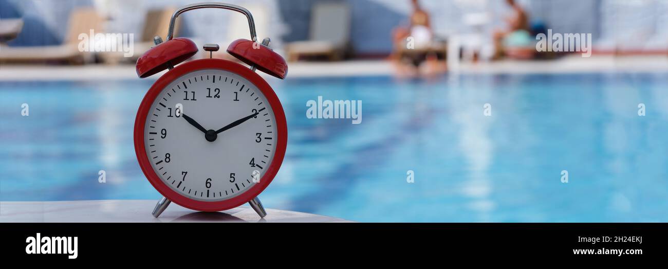 Red analog alarm clock with blurred background of relaxation pool Stock ...