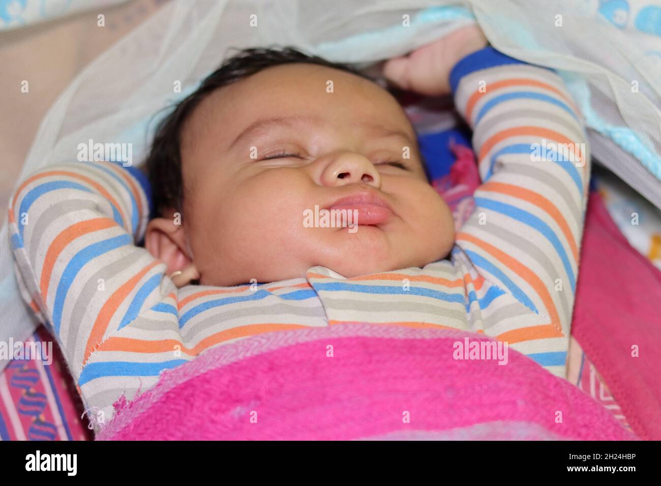 Close-up of An indian little newborn innocent baby sleeping in a funny ...