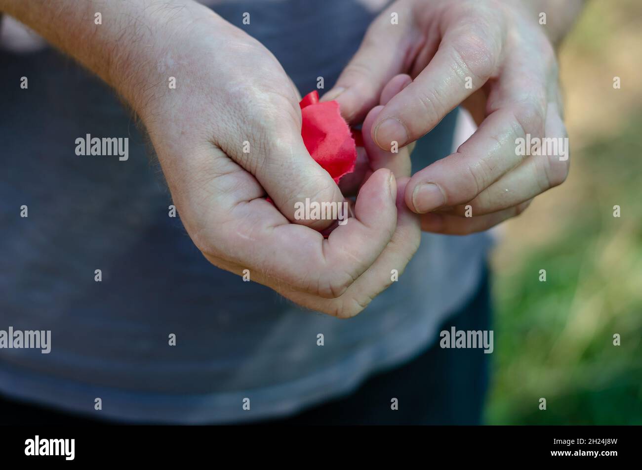 Adult Man nervously clutches a piece of red paper. Hands holding a ...
