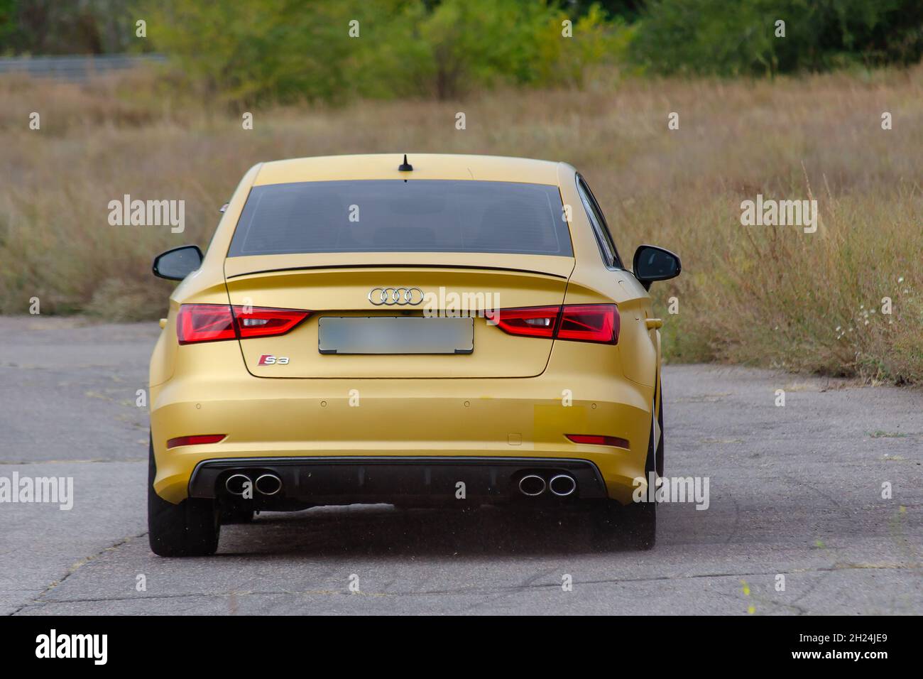 Rear view Yellow sedan drives at high speed on a paved road. Audi RS3 ...