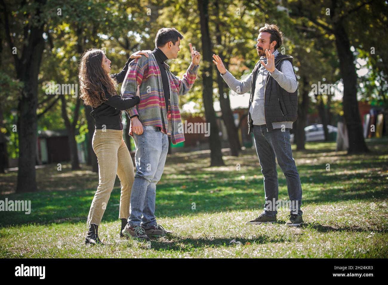 Two aggressive, angry, nervous and upset men in a quarrel and a woman ...
