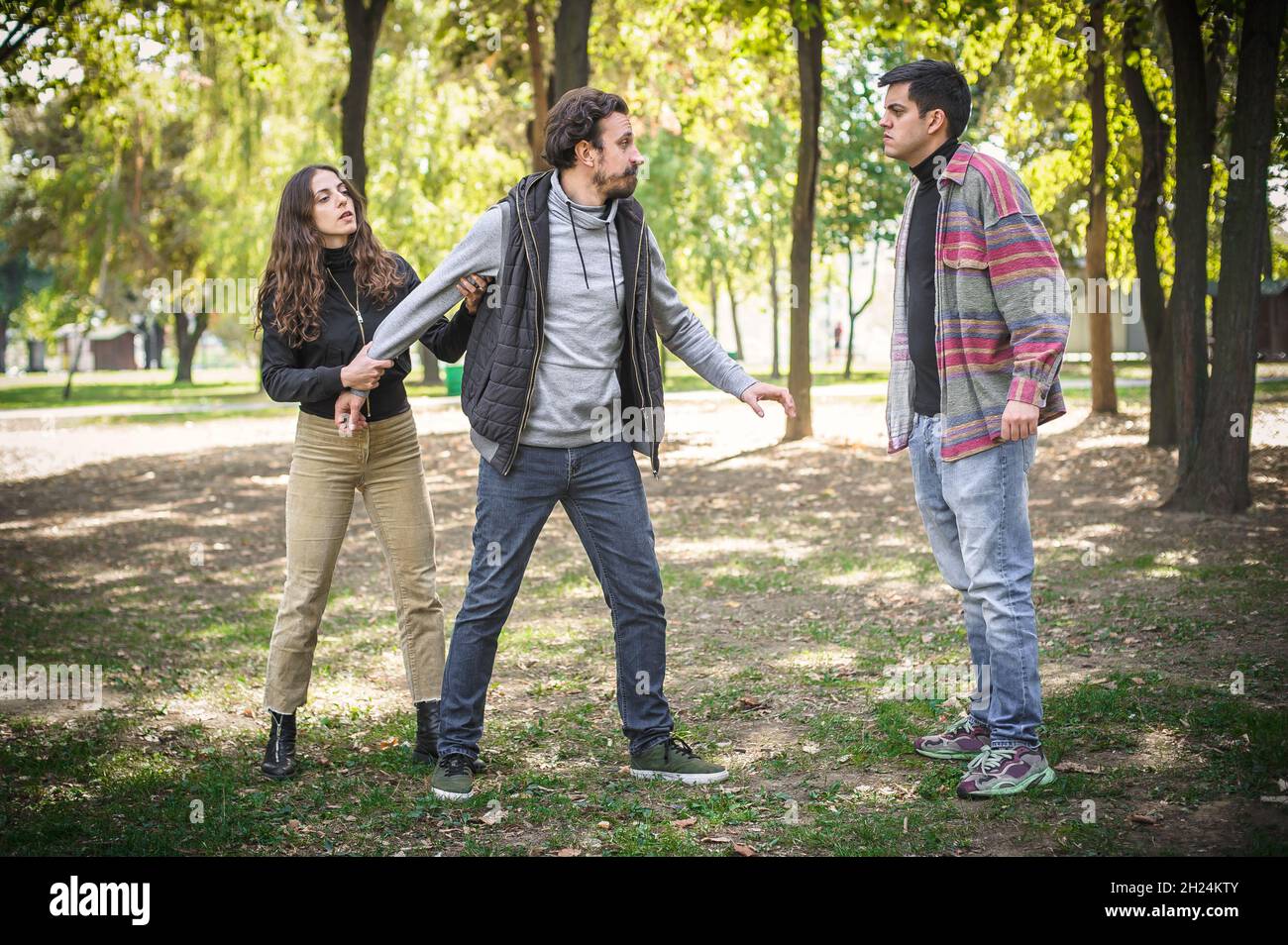 Two aggressive, angry, nervous and upset men in a quarrel and a woman ...