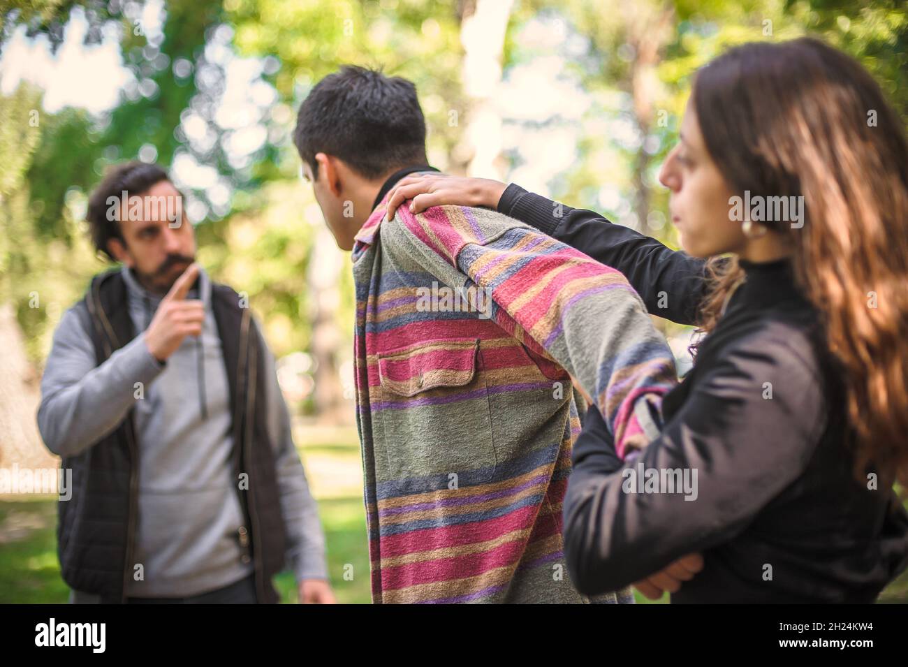 Two aggressive, angry, nervous and upset men in a quarrel and a woman ...