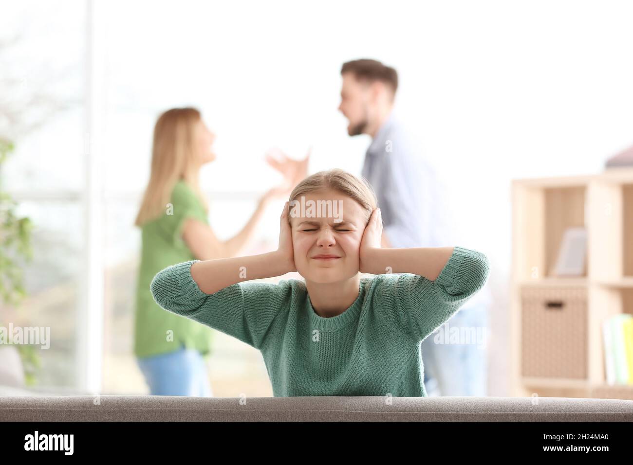 Little unhappy girl sitting on sofa while parents arguing at home Stock ...