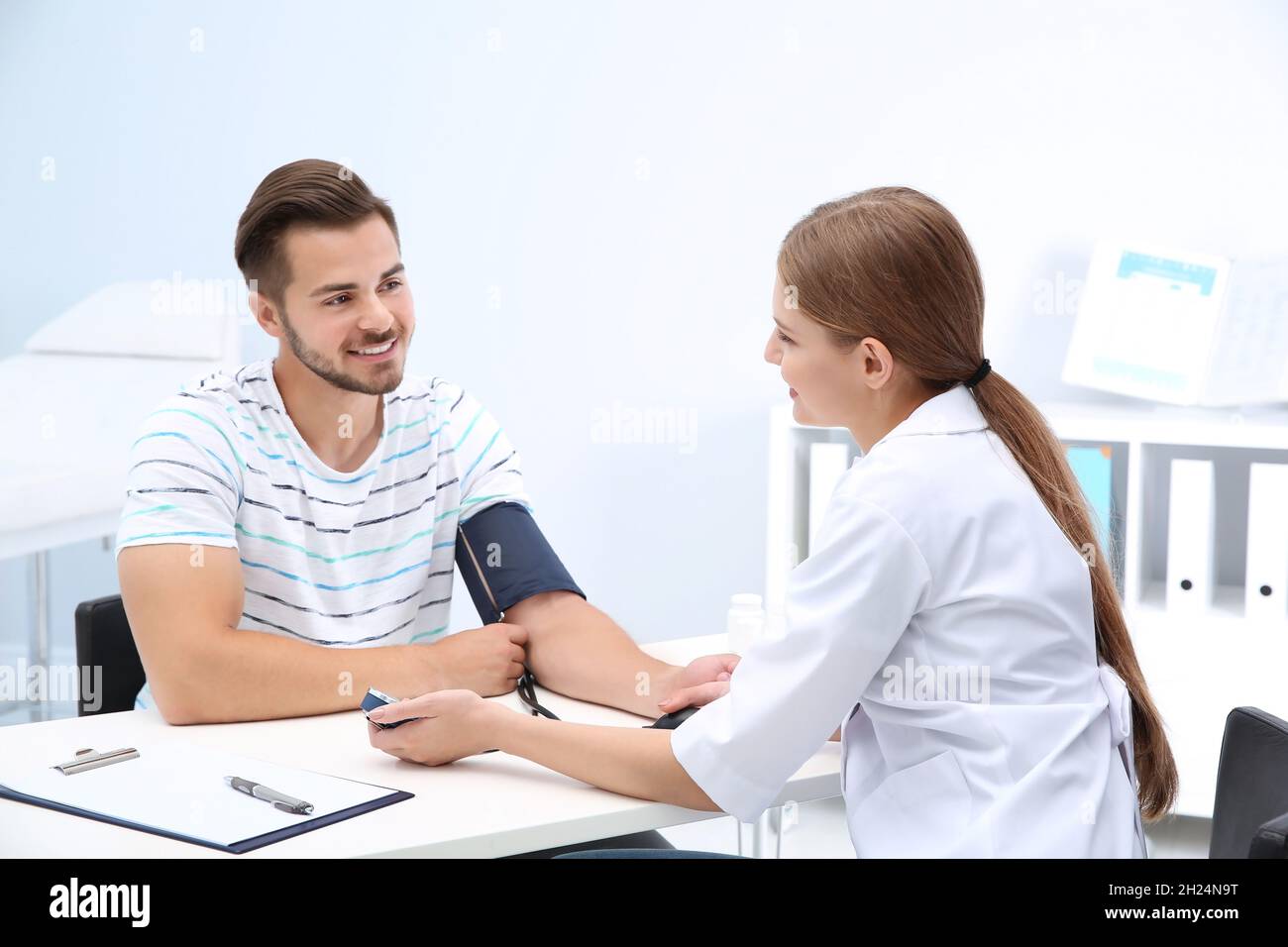 Doctor checking young man's pulse in hospital Stock Photo - Alamy