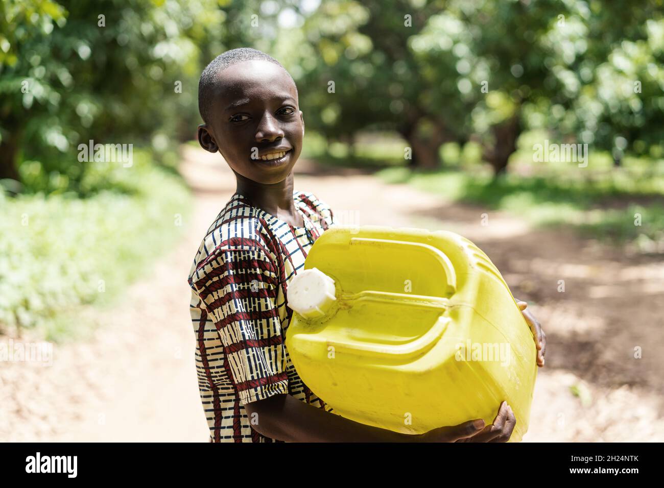 Cute little black African boy clutching a big water canister in his ...