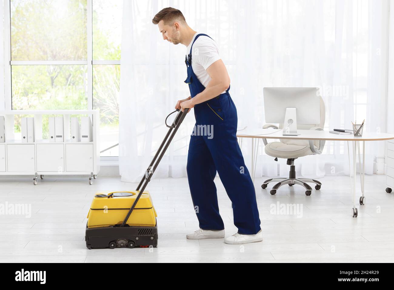 Male worker with floor cleaning machine indoors Stock Photo - Alamy