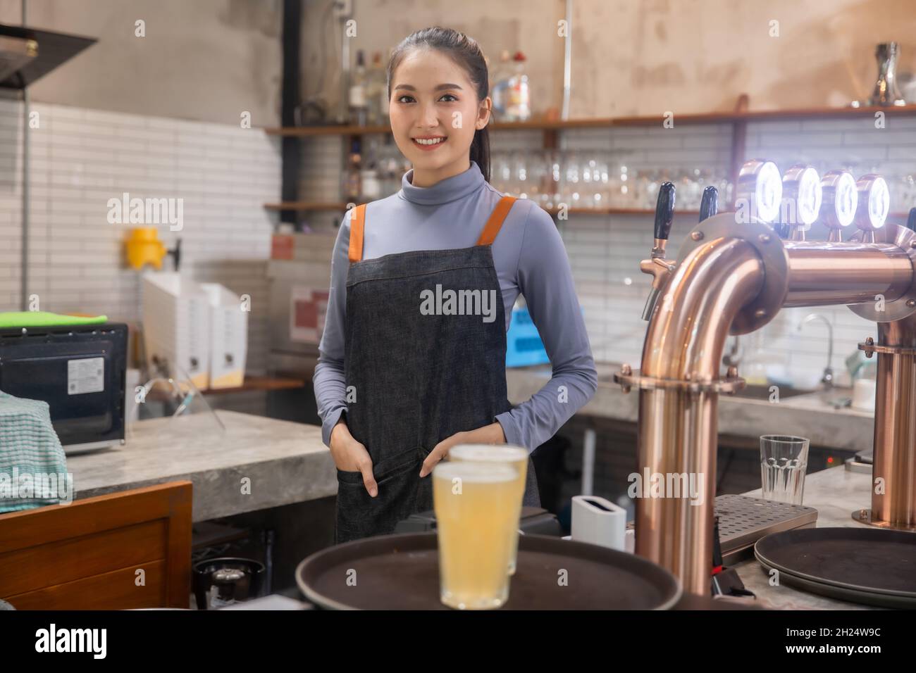 Portrait of Asian bartender girl hand at beer tap pouring , waitress or ...