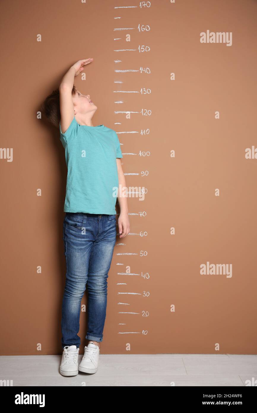 Little boy measuring his height near color wall Stock Photo - Alamy