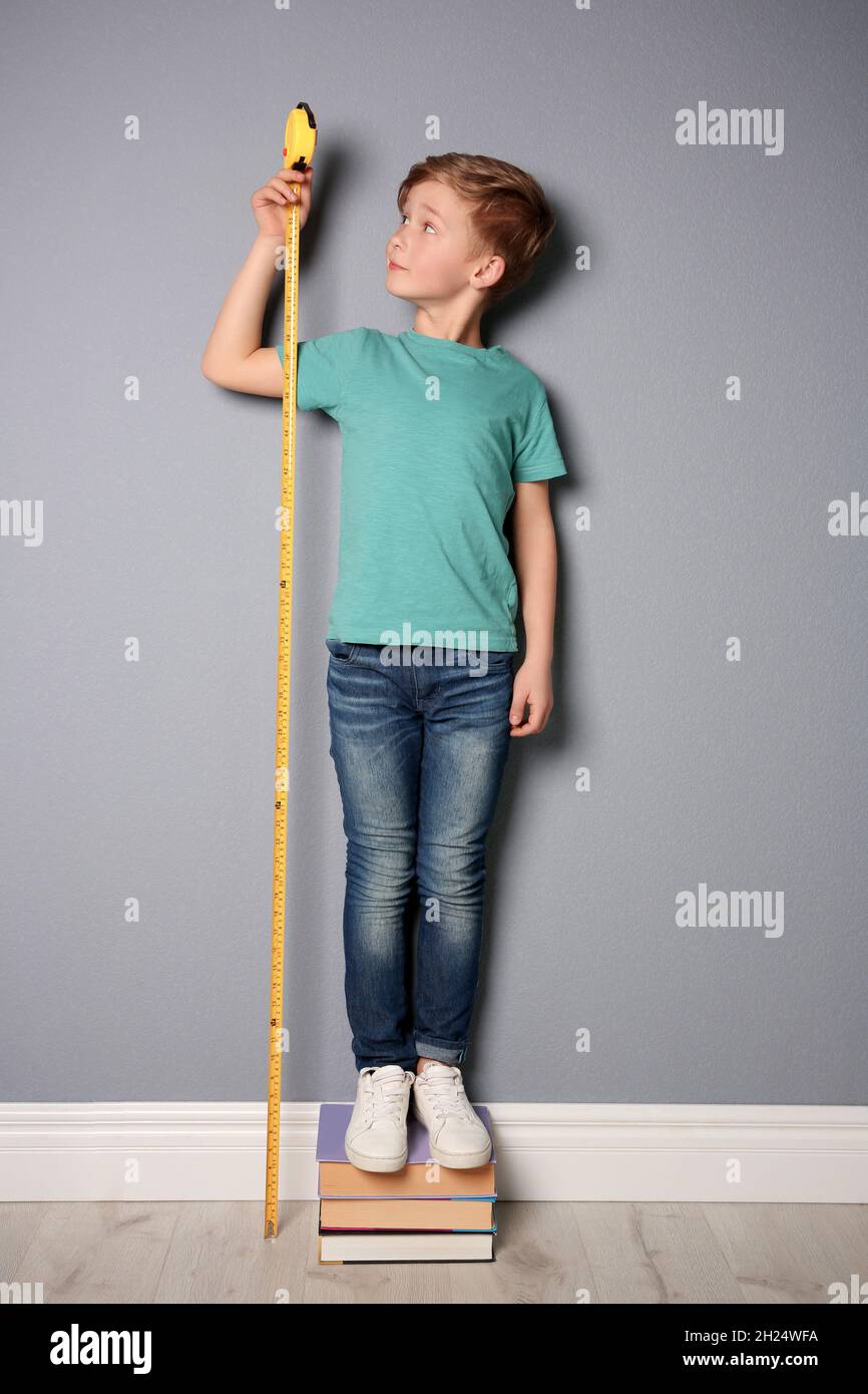 Little boy measuring his height near grey wall Stock Photo - Alamy
