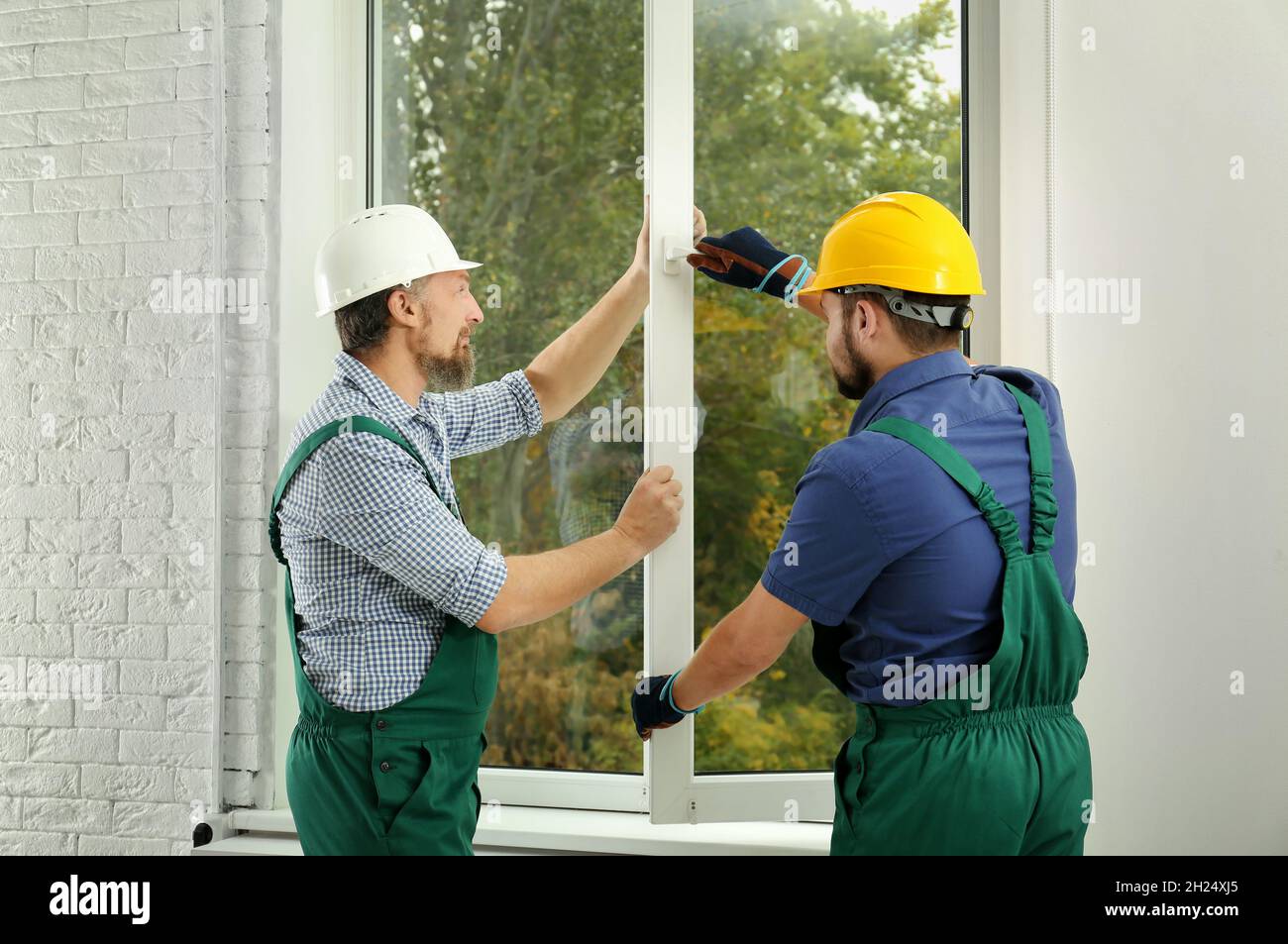 Construction workers installing new window in house Stock Photo - Alamy
