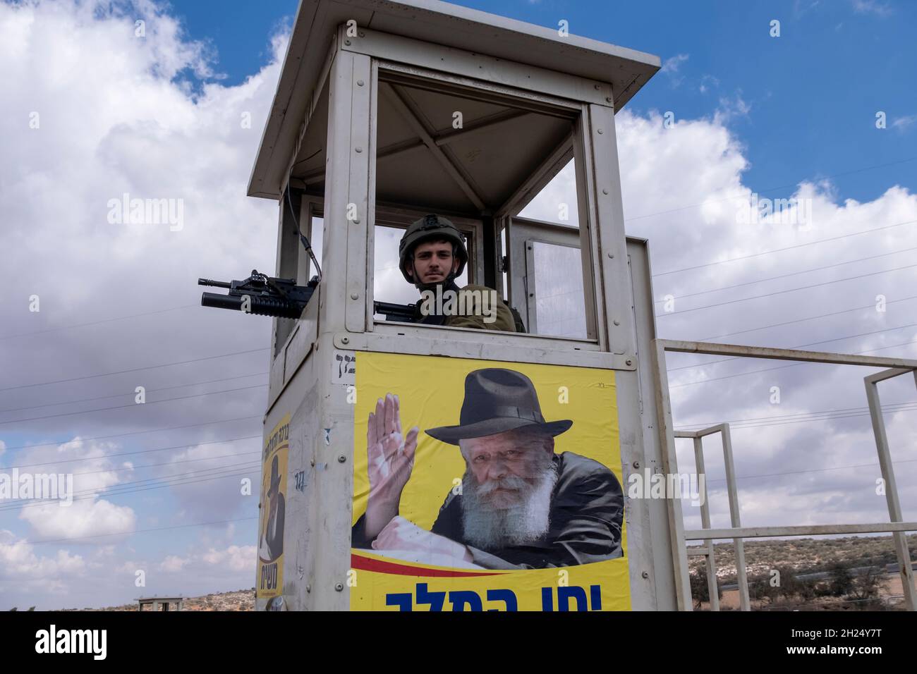 An Israeli soldier stands guard in a military watchtower with the image ...