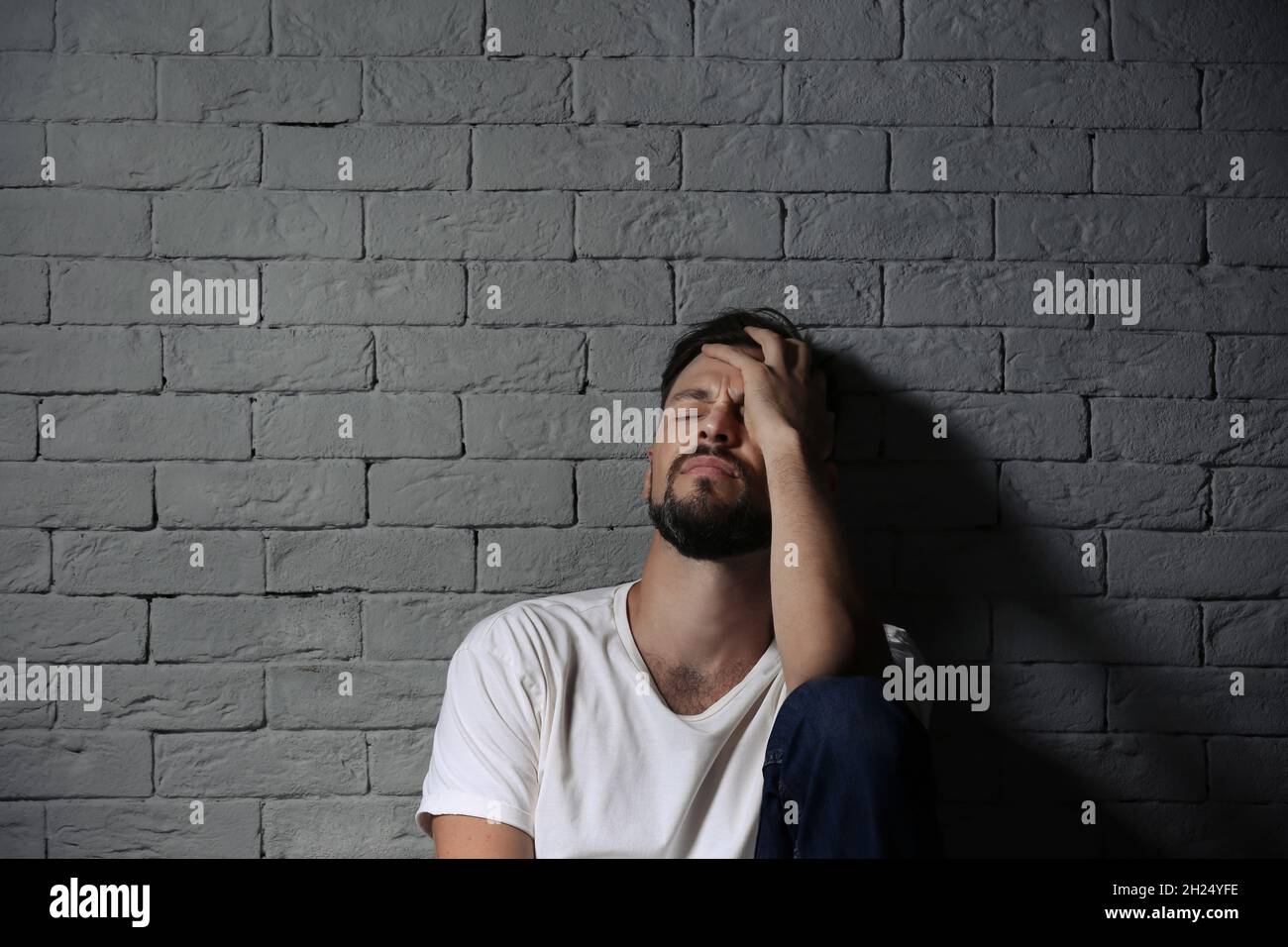 Lonely man suffering from depression near brick wall Stock Photo - Alamy
