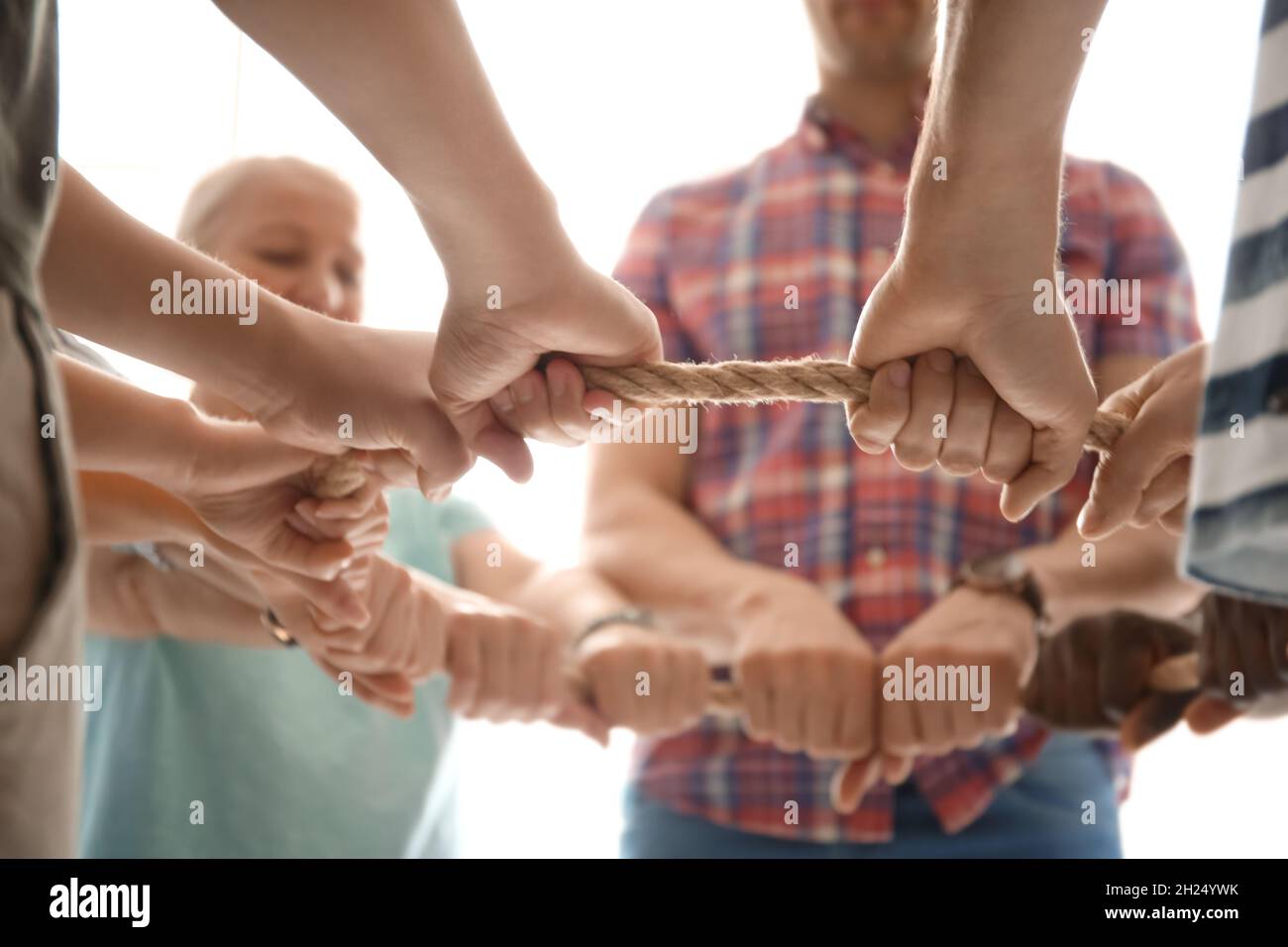 People holding rope together on light background, closeup of hands ...