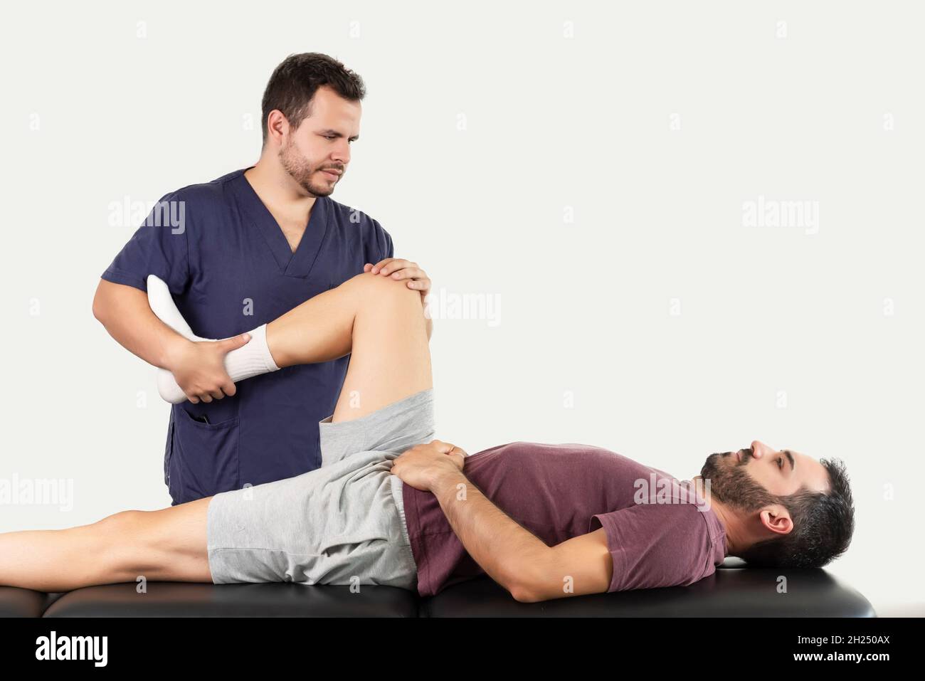 Physiotherapist performing mobility exercises on the leg of a patient ...