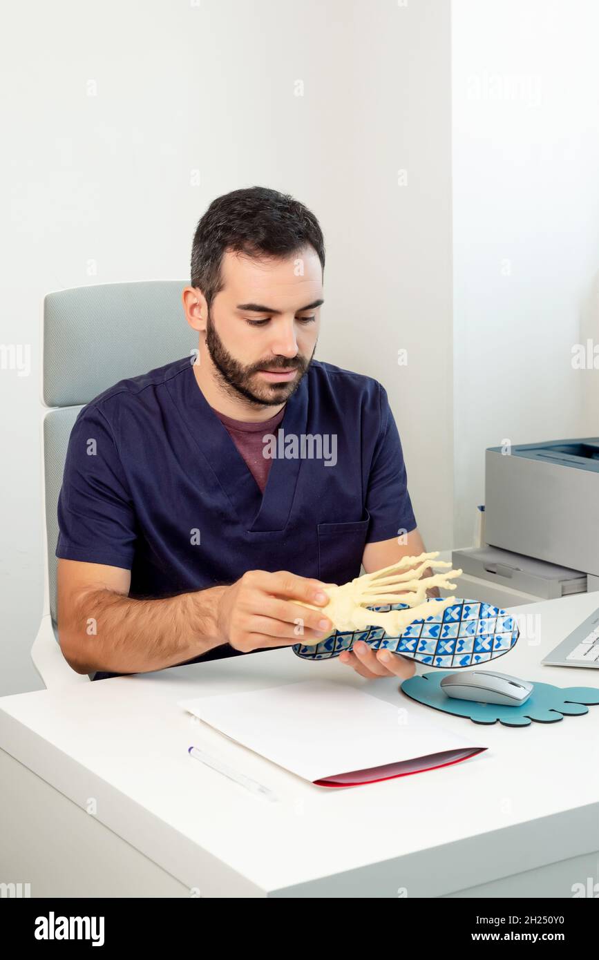 Doctor in his office showing a foot skeleton and an insole to explain ...