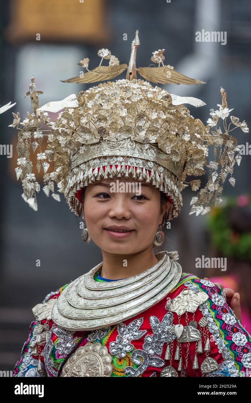 A young woman poses in the traditional ceremonial dress of the Tujia ...