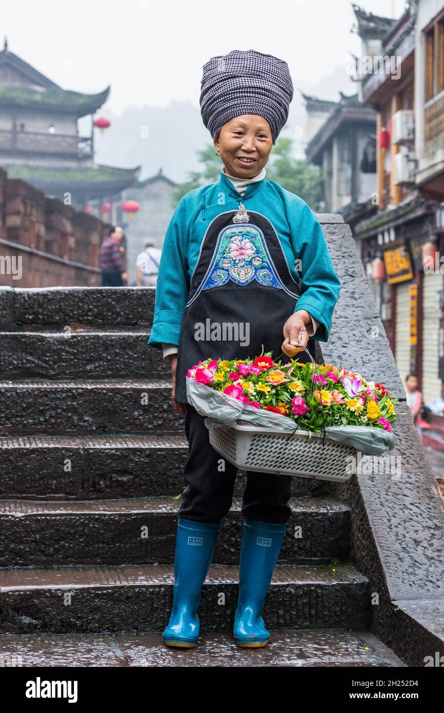 A woman in the traditional attire of the Tujia ethnic minority selling ...