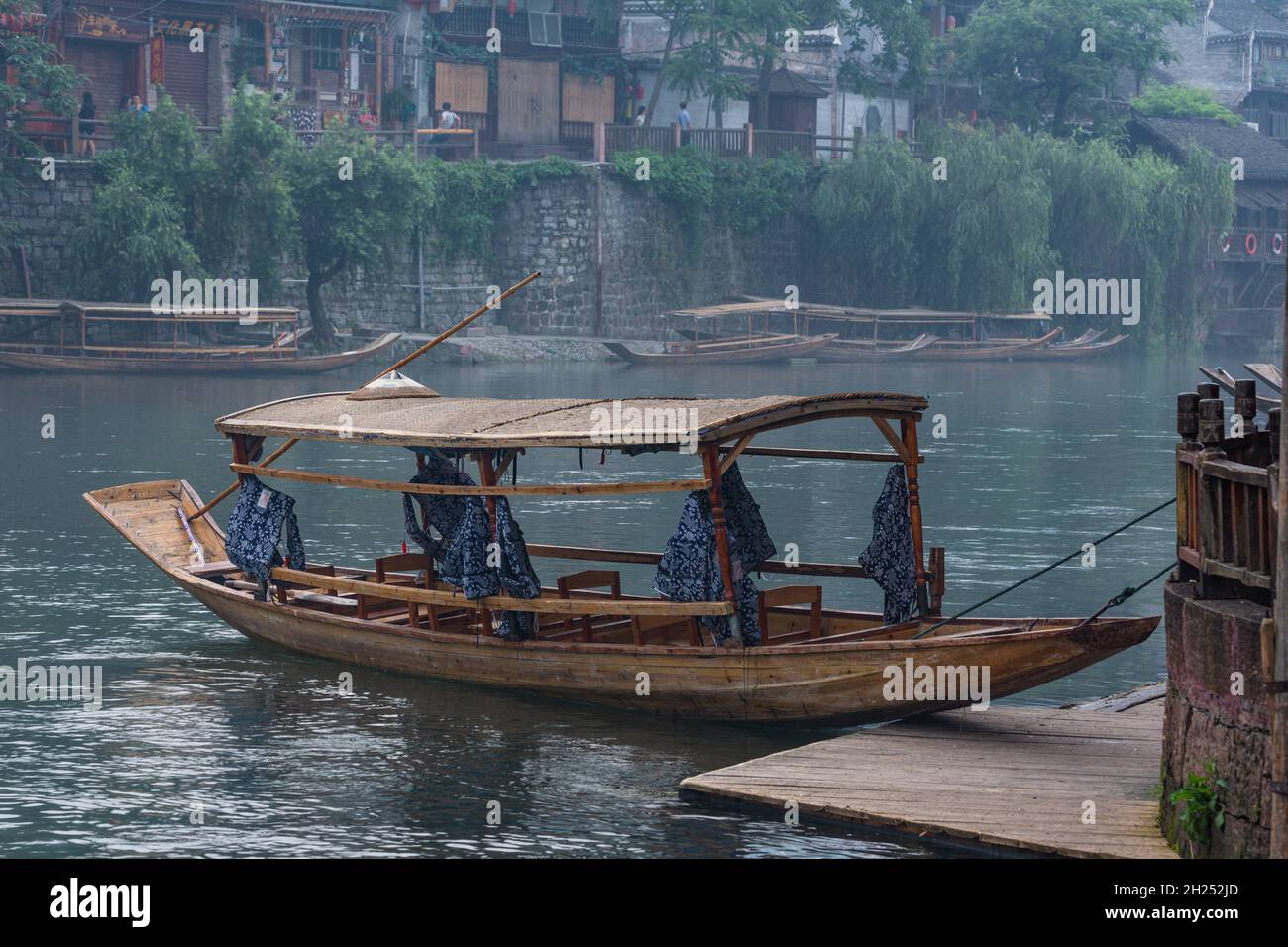 A covered tour boat docked on the Tuojiang River in Fenghuang, China ...