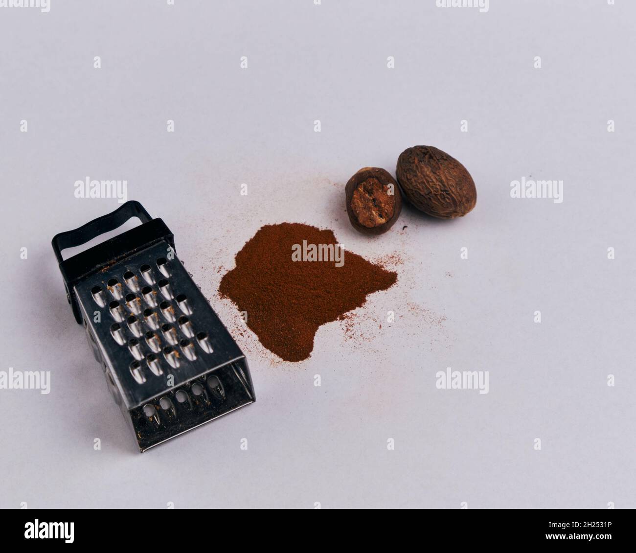 A small grater with cinnamon sticks and powder, isolated on a white ...