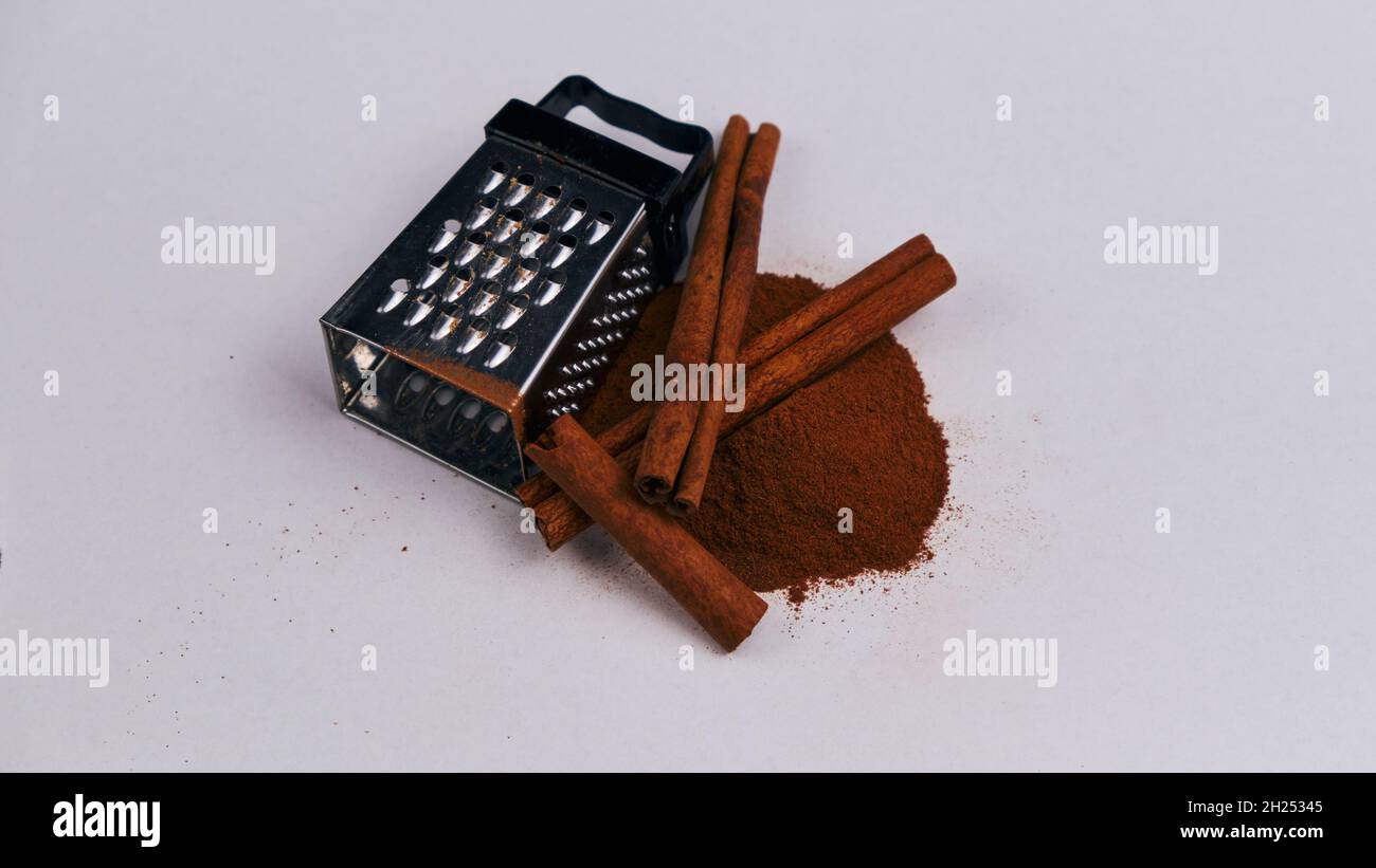 A small grater with cinnamon sticks and powder, isolated on a white ...
