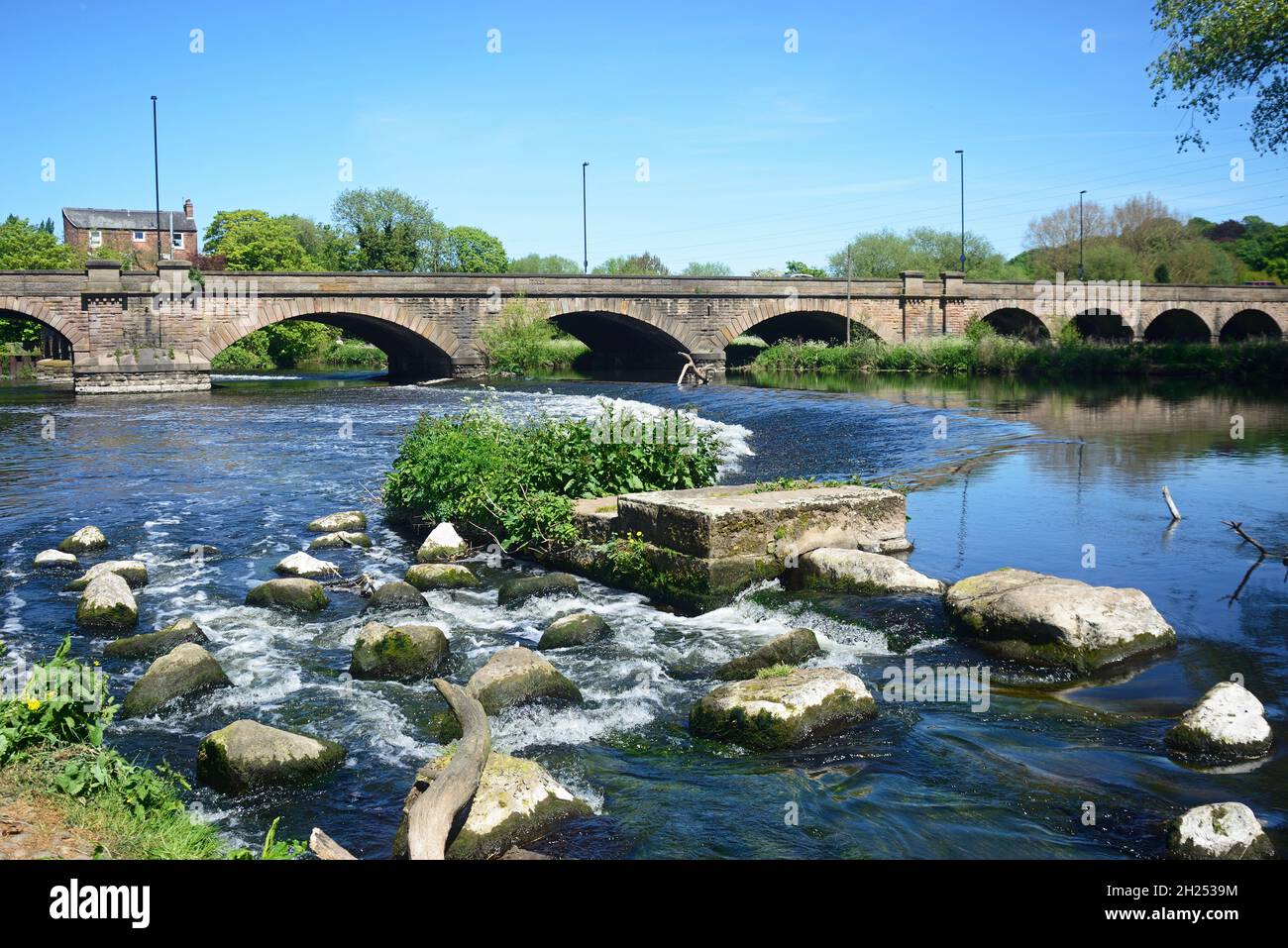 View across boulders and the weir towards the Trent Bridge road bridge ...