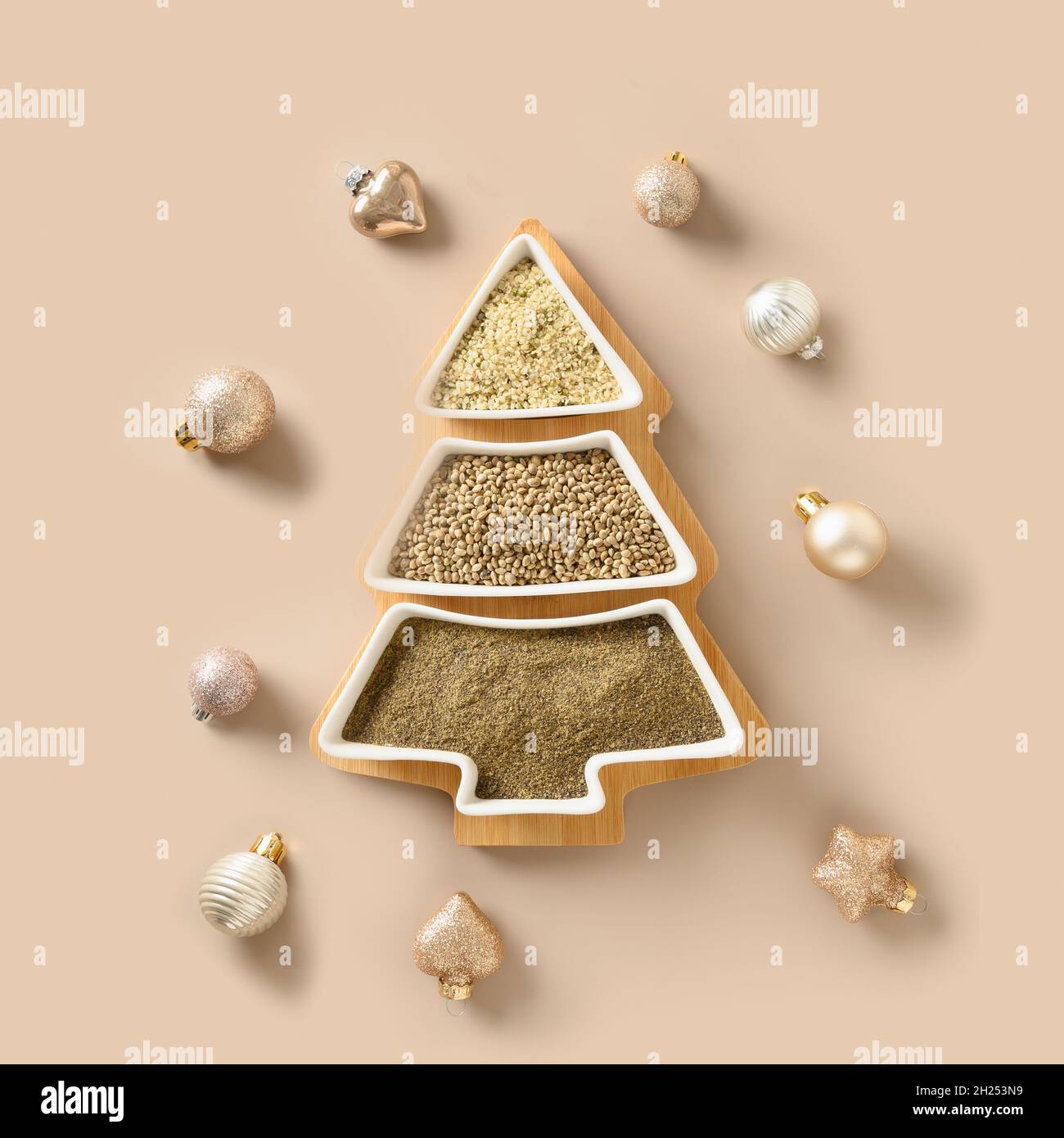 Hemp seeds, flour, kernels in plate shape of Christmas tree on pastel ...