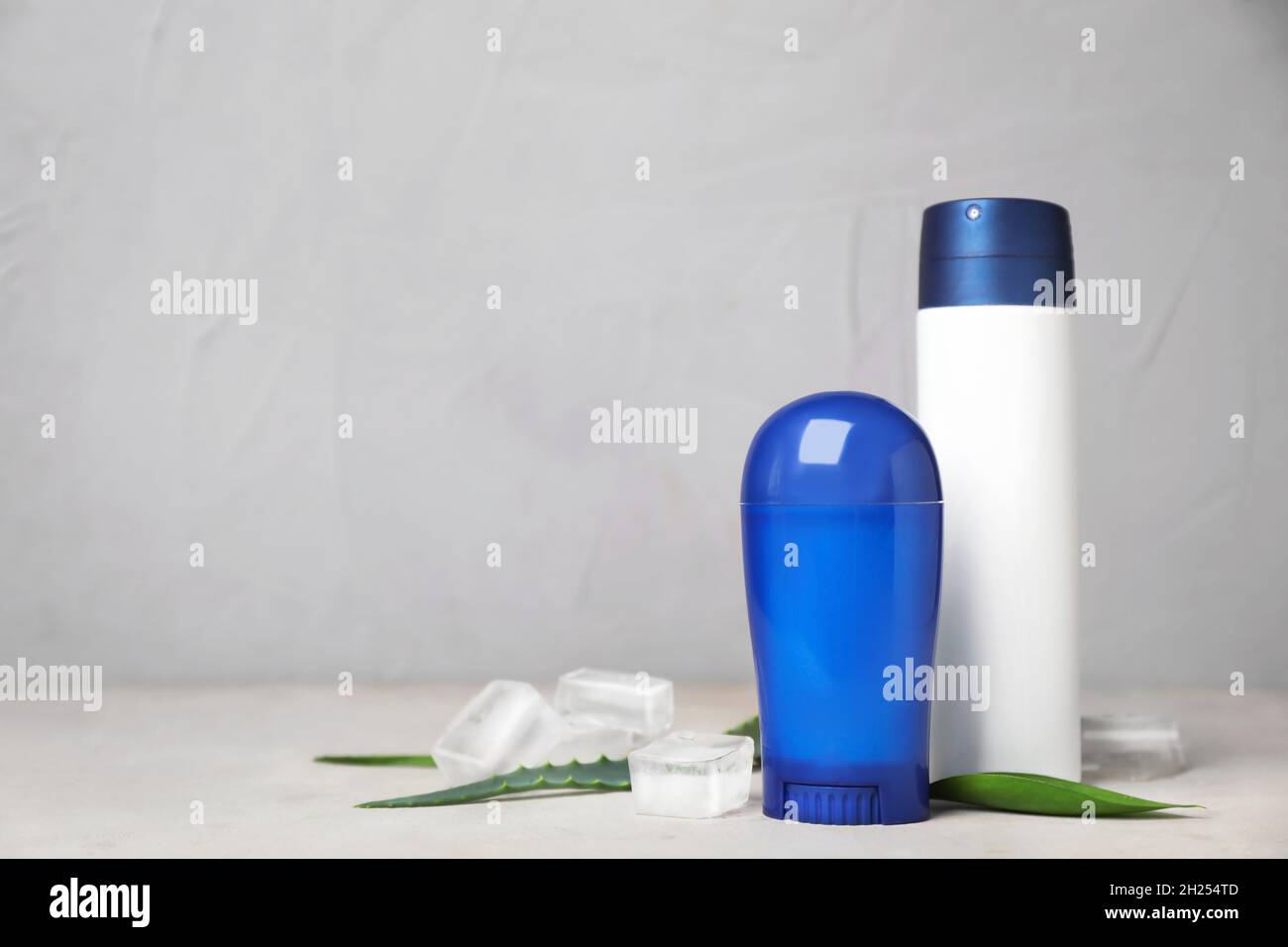 Different deodorants, ice cubes and aloe on table. Personal hygiene ...