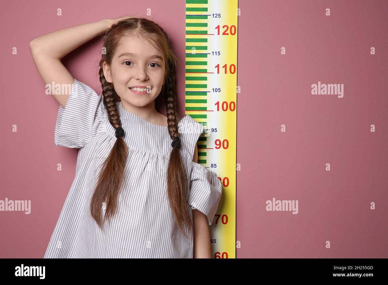 Little girl measuring her height on color background Stock Photo - Alamy