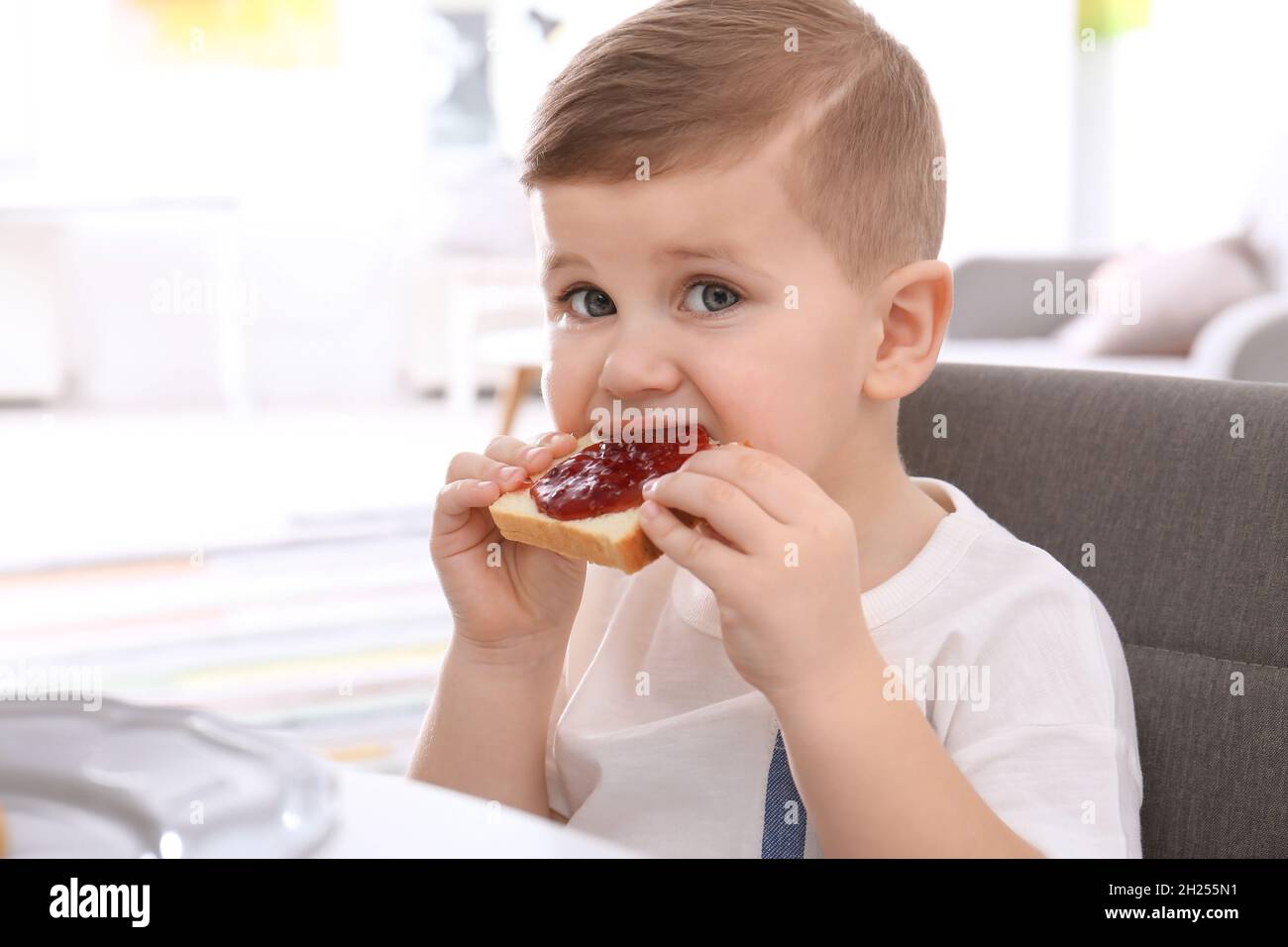 Cute little boy eating toast with sweet jam at table Stock Photo - Alamy